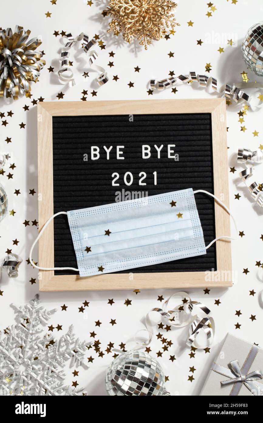 black letter board with text BYE BYE 2021 with decoration and mask on ...