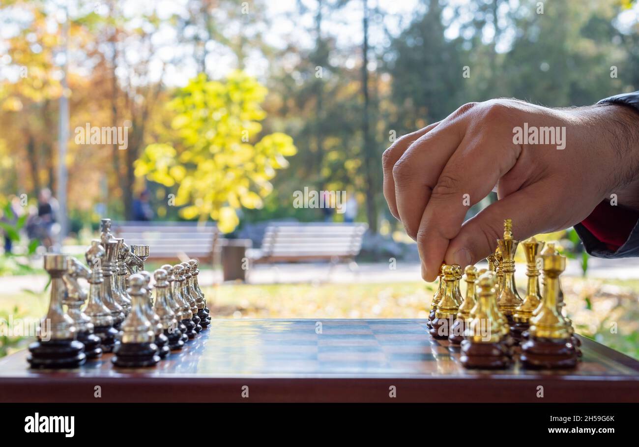 Outdoor chess game. Chessboard with figures, close-up, hand makes the ...