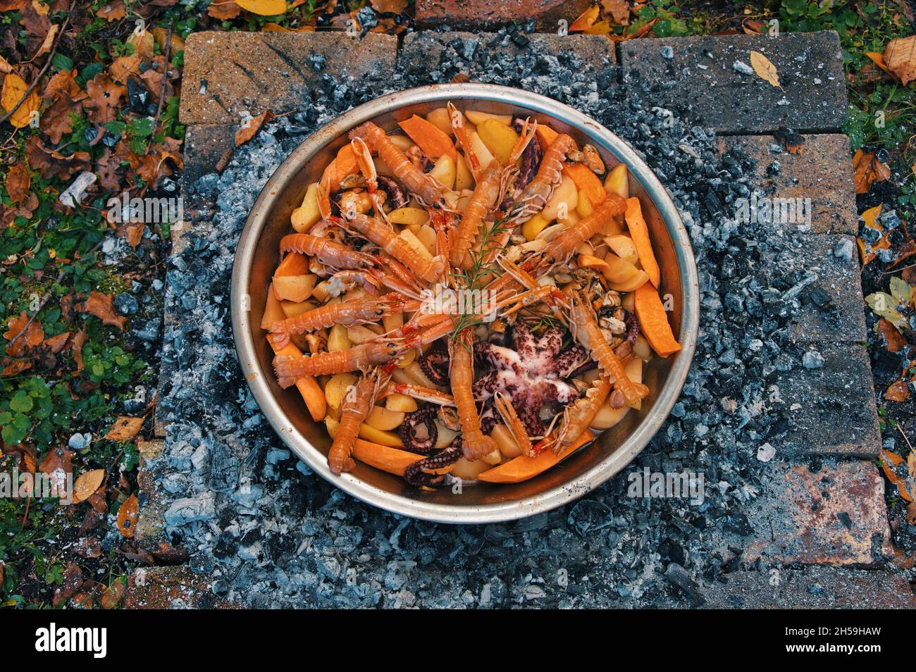 Flat lay of octopus and shrimps with potatoes in metal pan on glowing ...