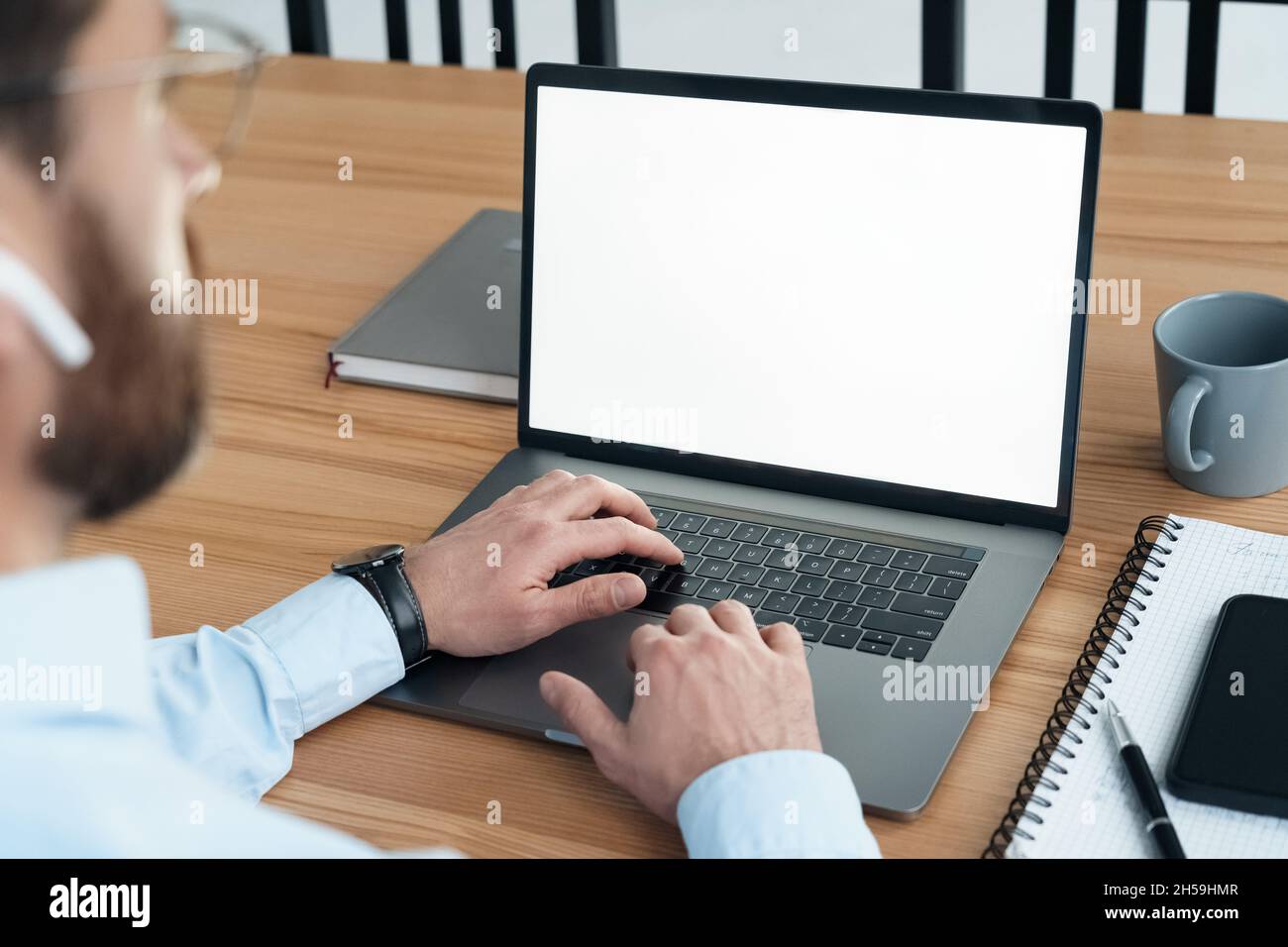 Rear view shoulder over on businessman working on laptop looking at ...