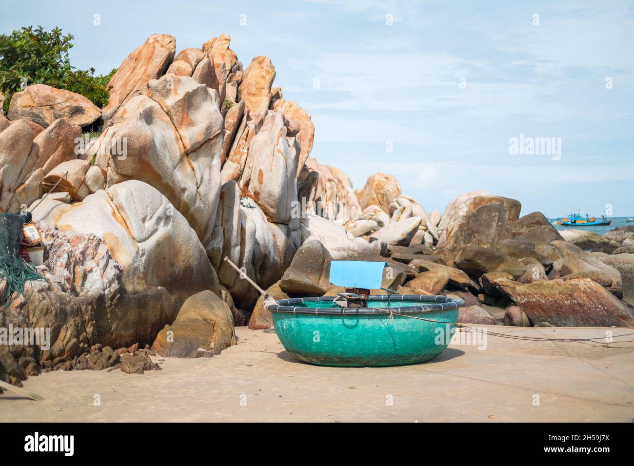 Round colourful Vietnamese fishing boat stands on the picturesque beach ...