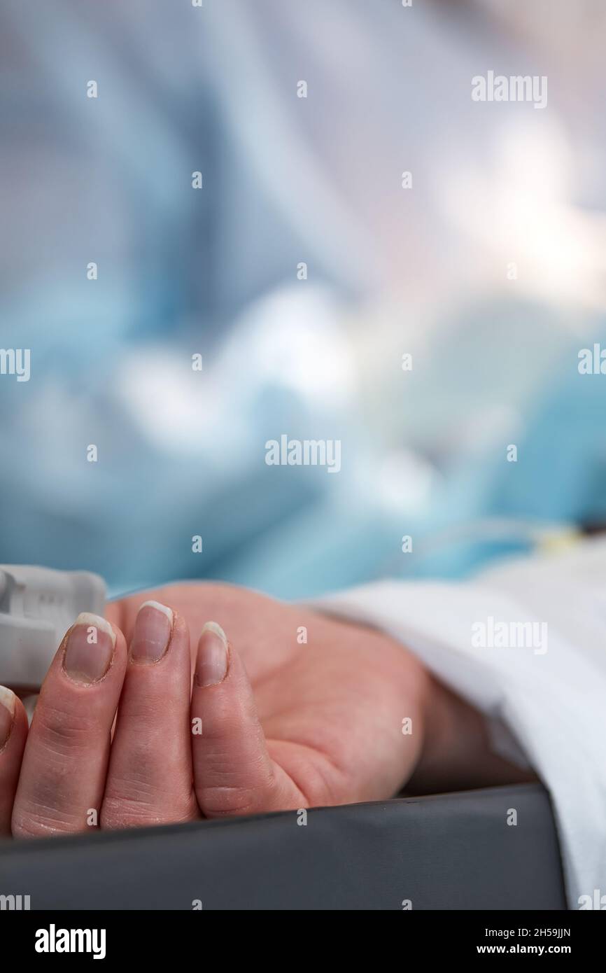 The patient's hand is under the IV with a pulse oximeter on the finger ...