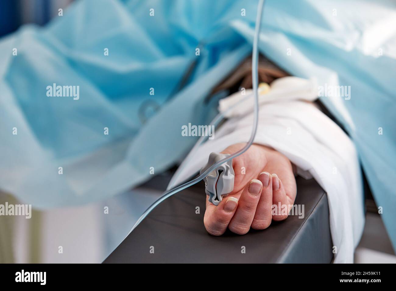 The patient's hand is under the IV with a pulse oximeter on the finger ...
