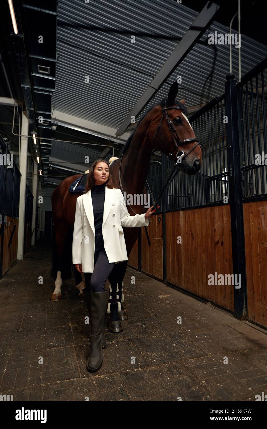 Portrait of smiling female jockey standing by horse in stable Stock ...
