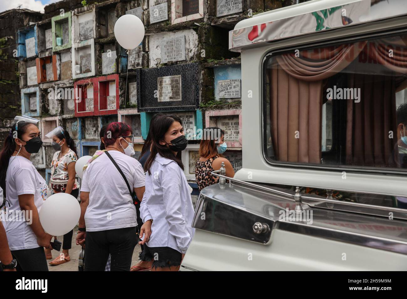 People attend a burial ceremony as others visit their departed loved ...