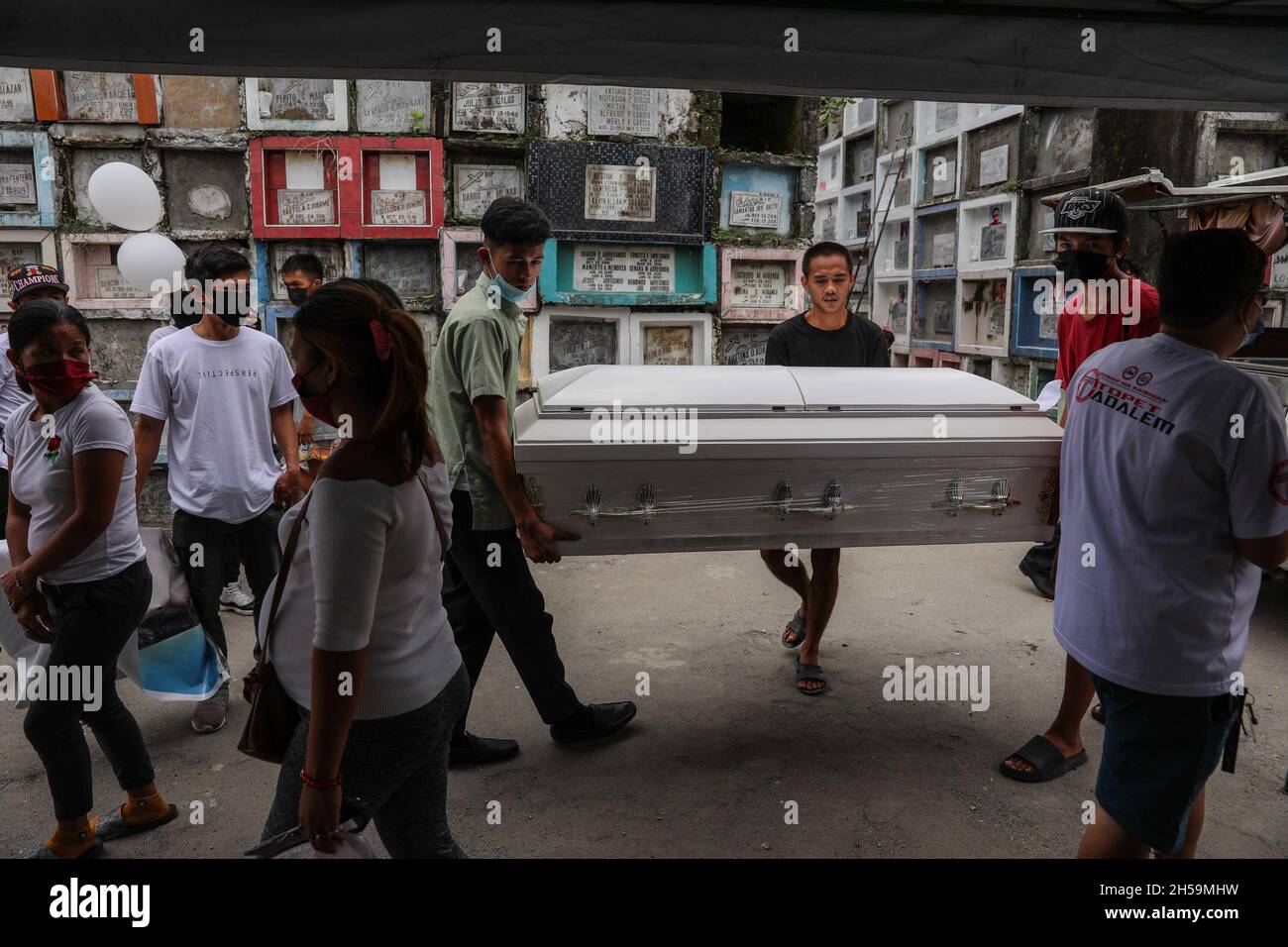 People attend a burial ceremony as others visit their departed loved ...