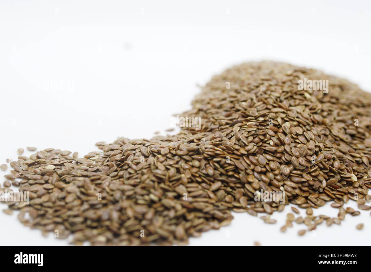 Horizontal close up of brown flaxseeds linseeds on a white background ...