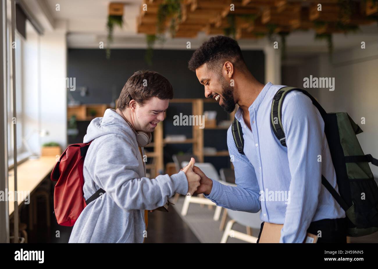 Young happy man with Down syndrome with his mentoring friend greeting ...
