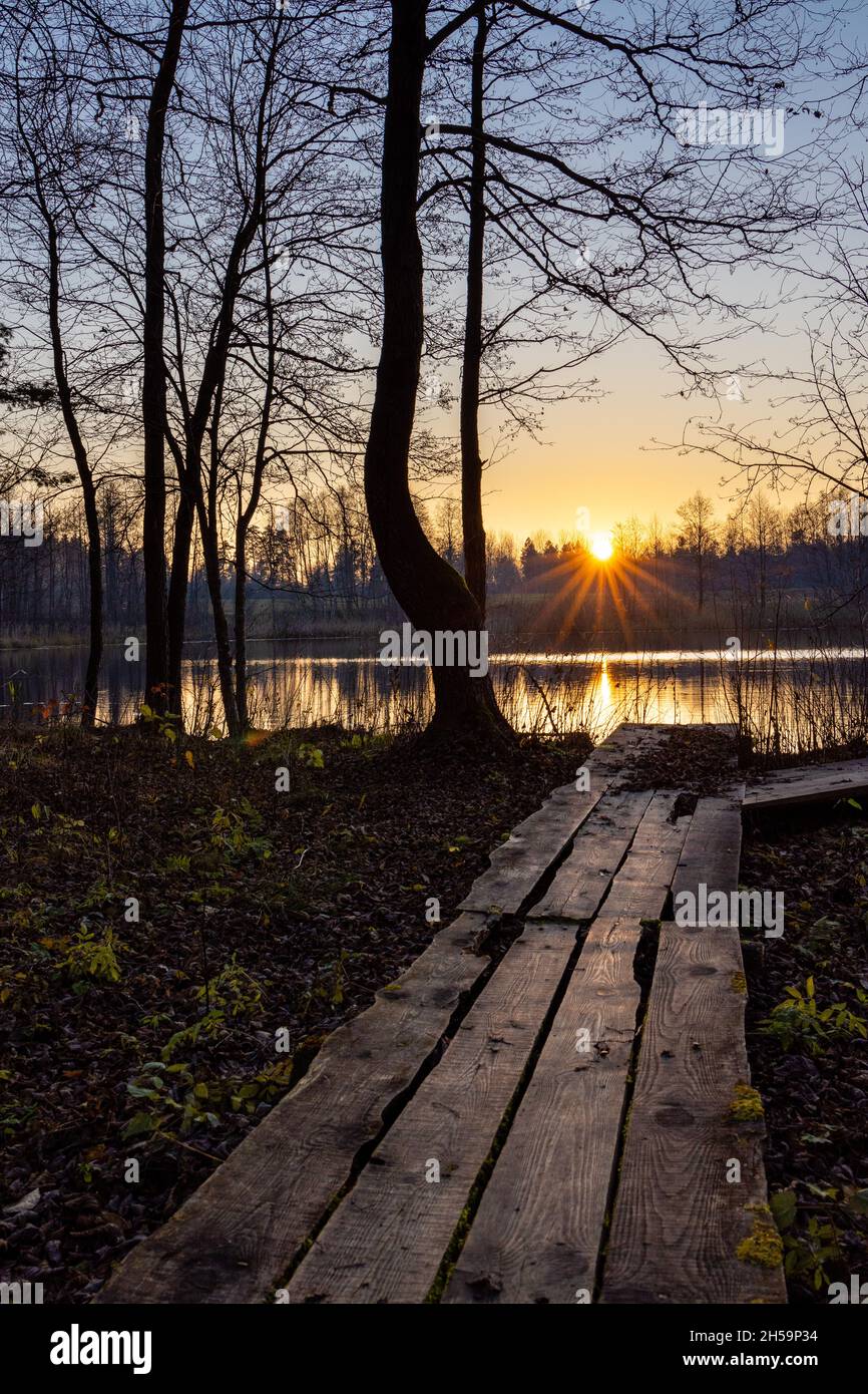Wooden deck leading to the lake. Beautiful sunset landscape, sun over ...