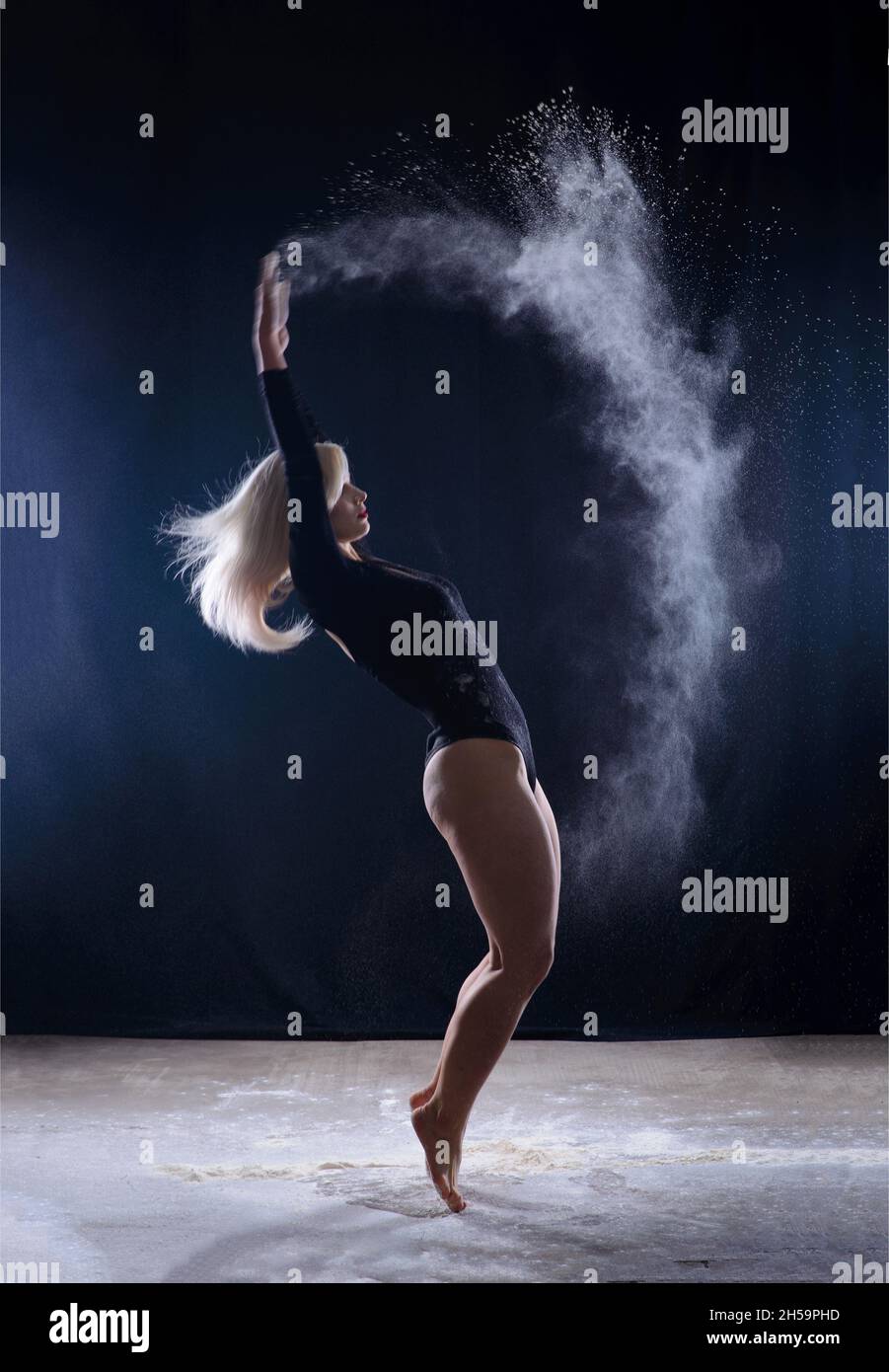 Plump blonde girl wearing black gymnastic bodysuit covered with clouds of the flying white ...