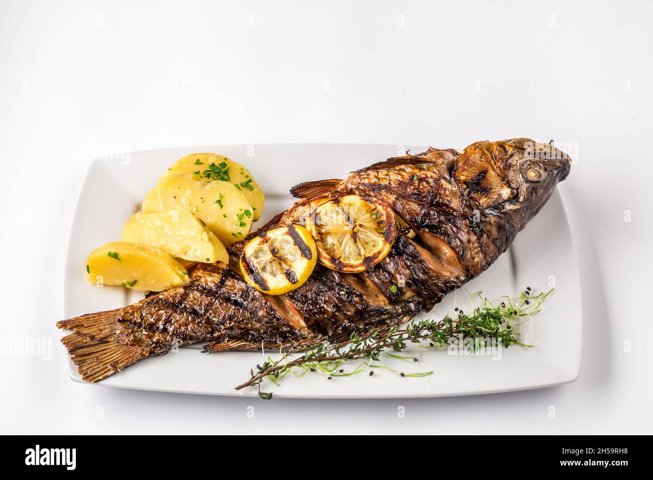 Grilled carp fish with rosemary potatoes and lemon, close up Stock ...