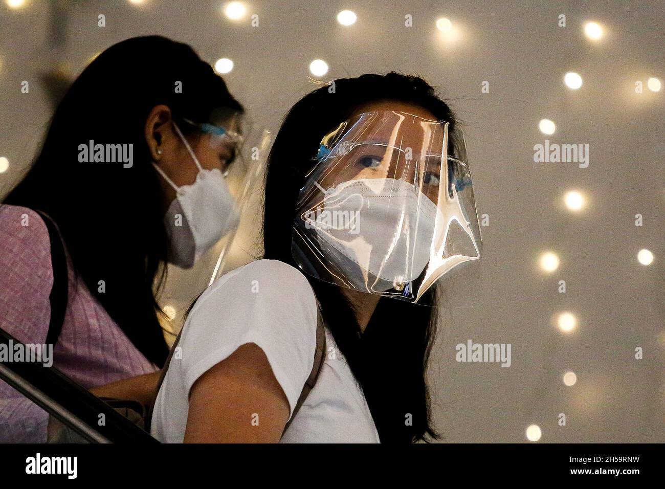 People wearing protective masks and face shields walk inside a shopping ...