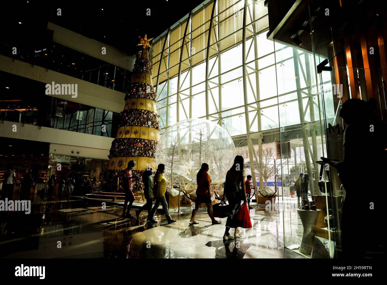 People wearing protective masks and face shields walk inside a shopping ...