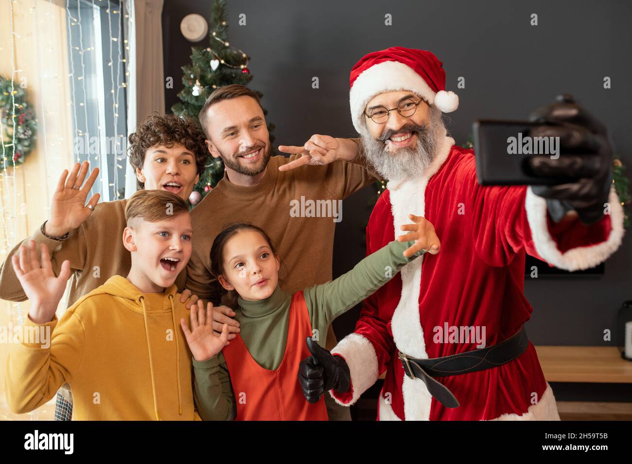Positive Santa Claus in eyeglasses showing thumb-up while photographing ...