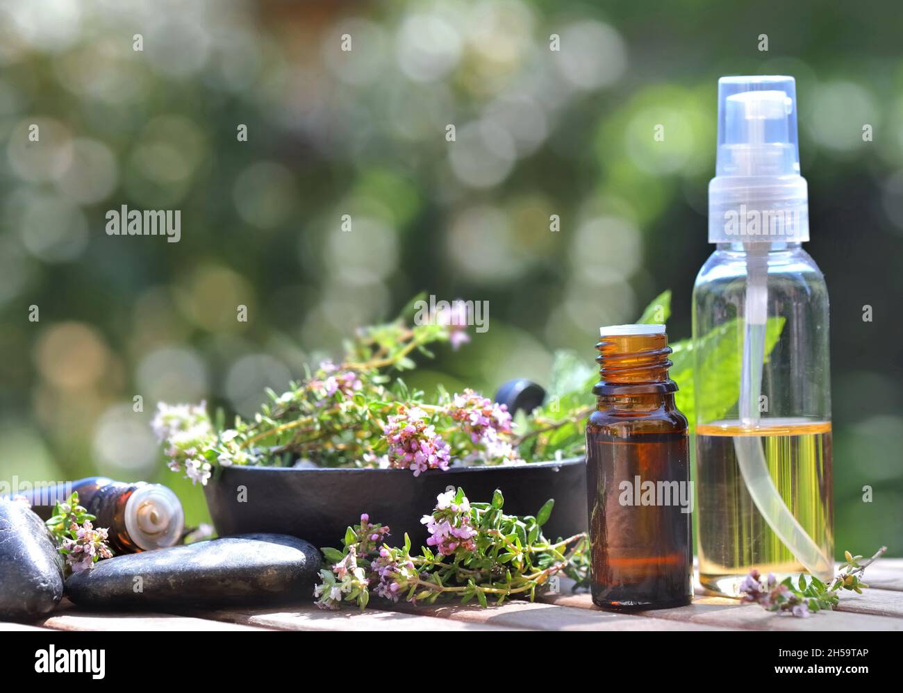 bottles of essential oil and flowers of aromatic herb on a table and on ...