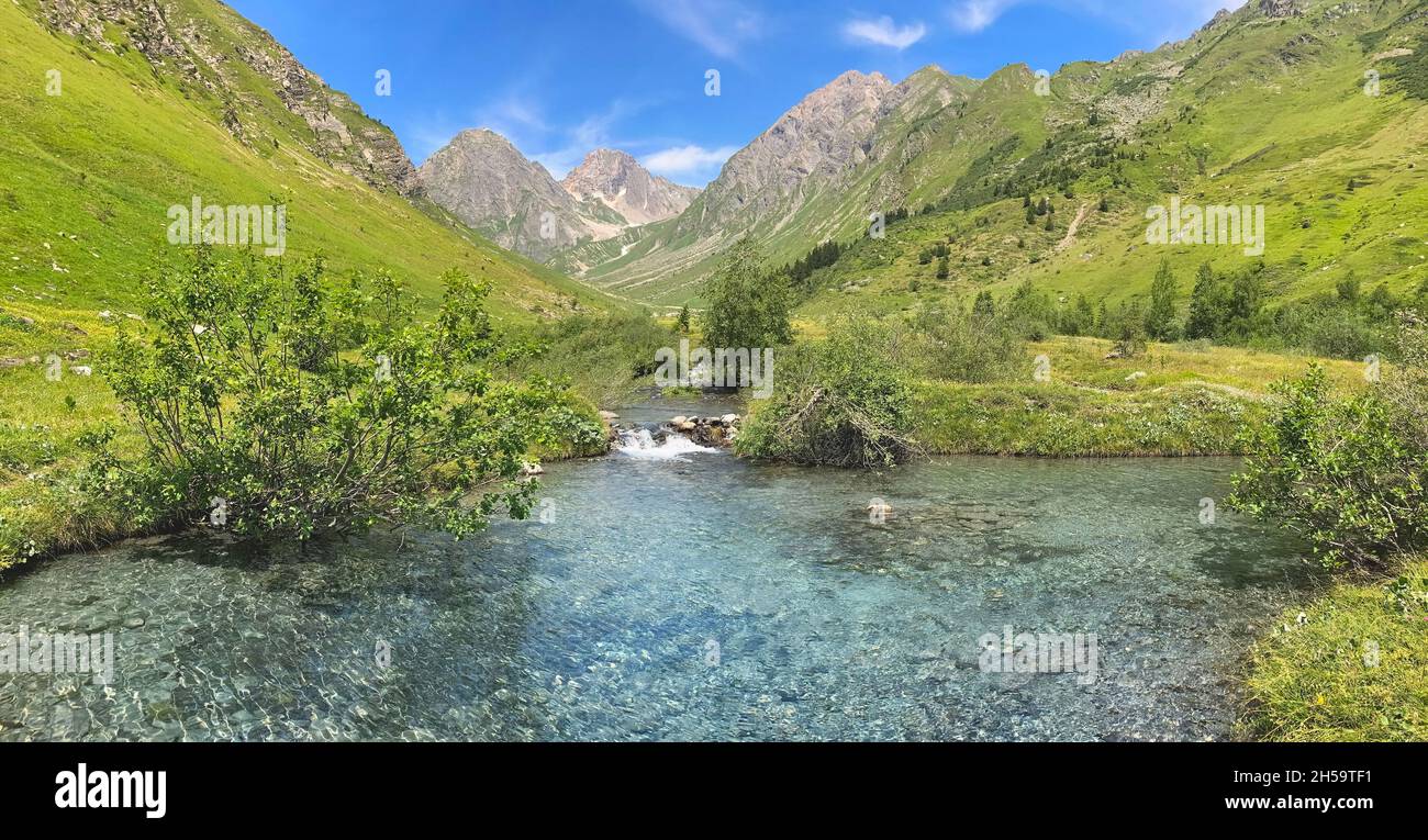 river in alpine valley with peak mountain background Stock Photo - Alamy