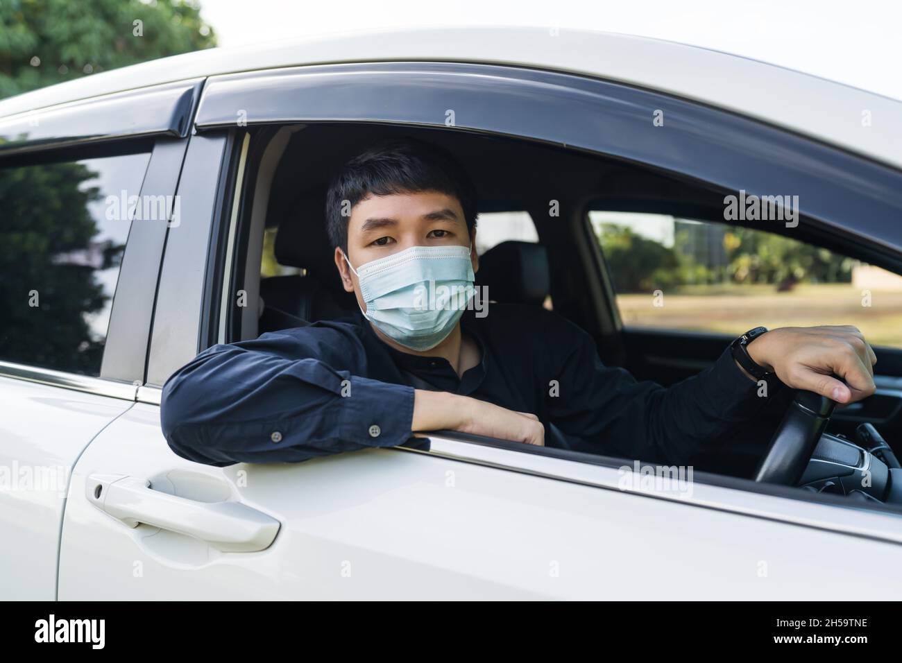 young man in medical mask driving a car. for protect covid-19 ...