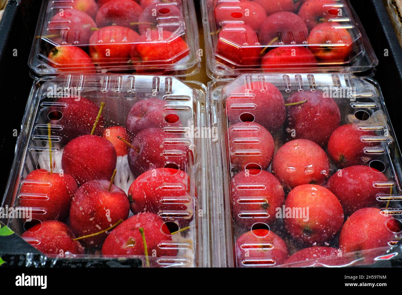 Top view of red ripe juicy apples in plastic containers at a fresh ...