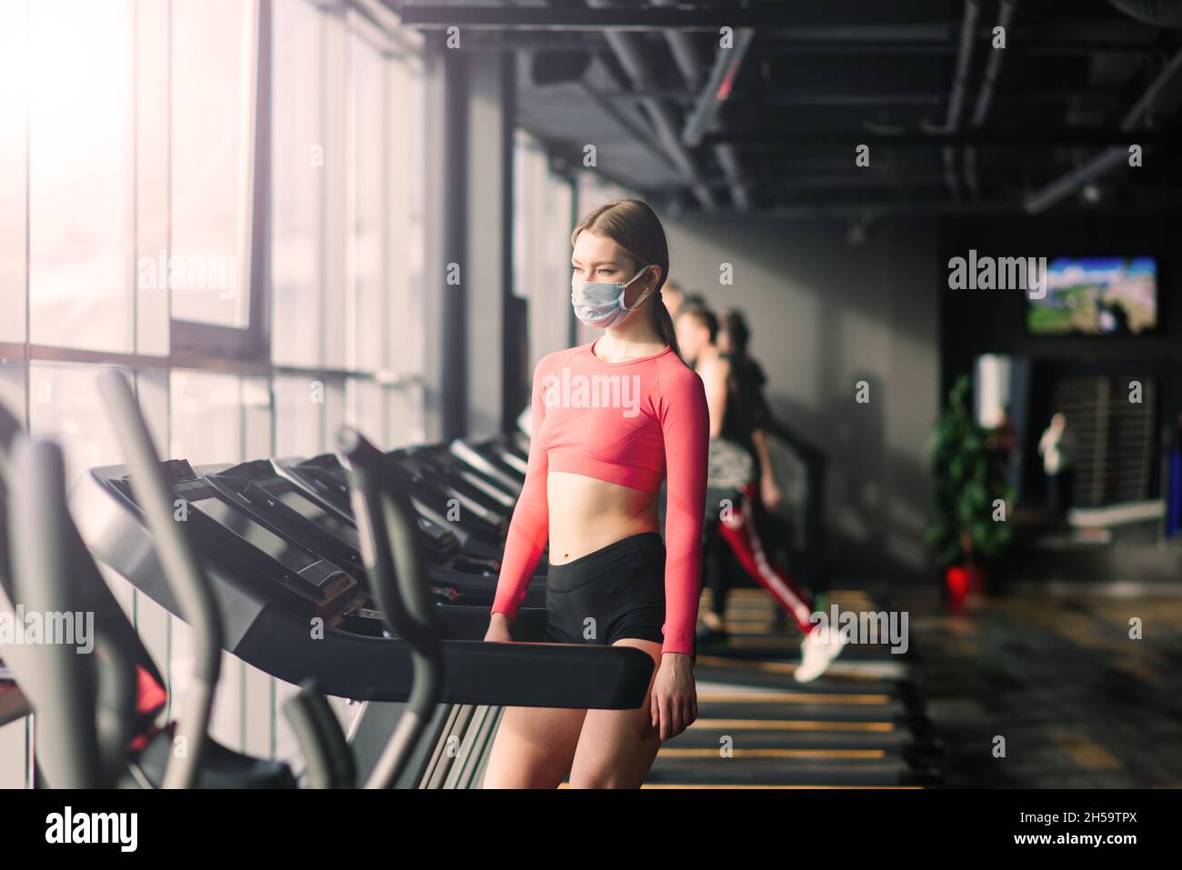 Woman wearing face mask exercise workout in gym during corona virus ...