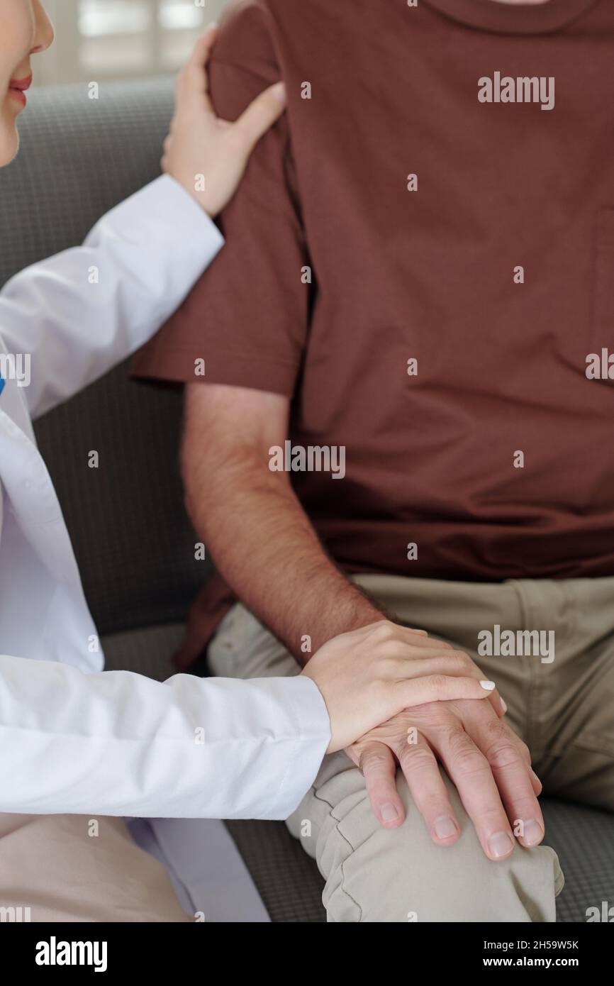Medical nurse touching arm of patient to support him after explaining ...