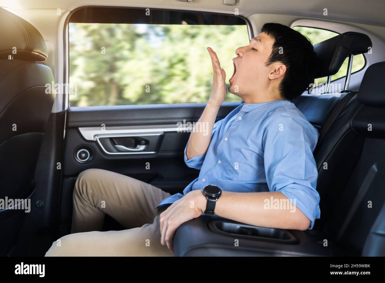 sleepy young man yawning while sitting in the back seat of car Stock ...