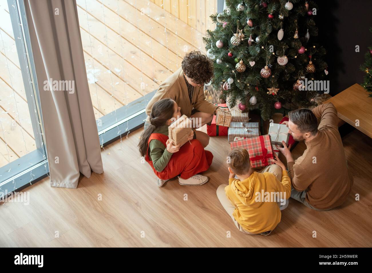 Above view of family with two children sitting on floor near Christmas ...