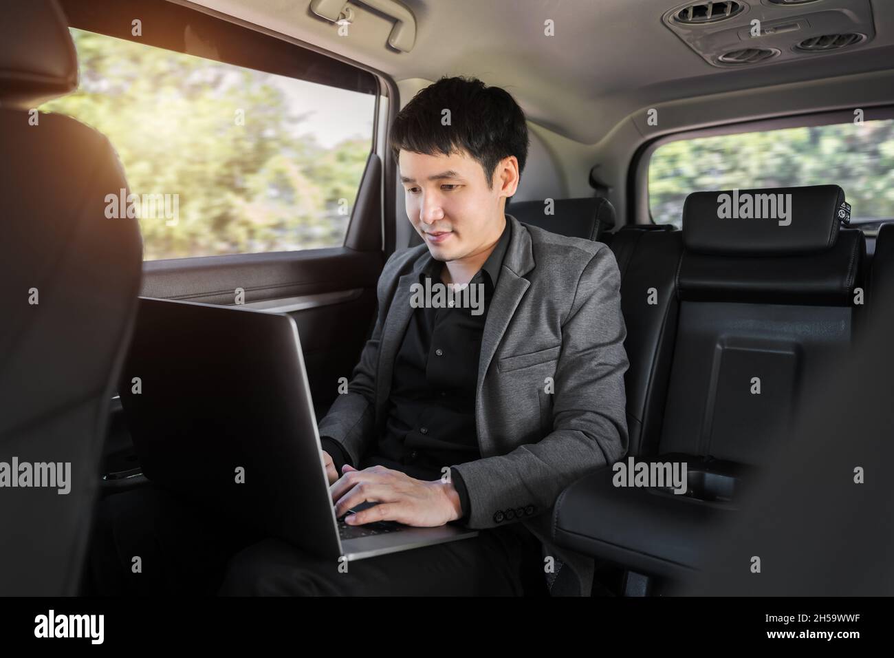 young business man using laptop computer while sitting in the back seat ...