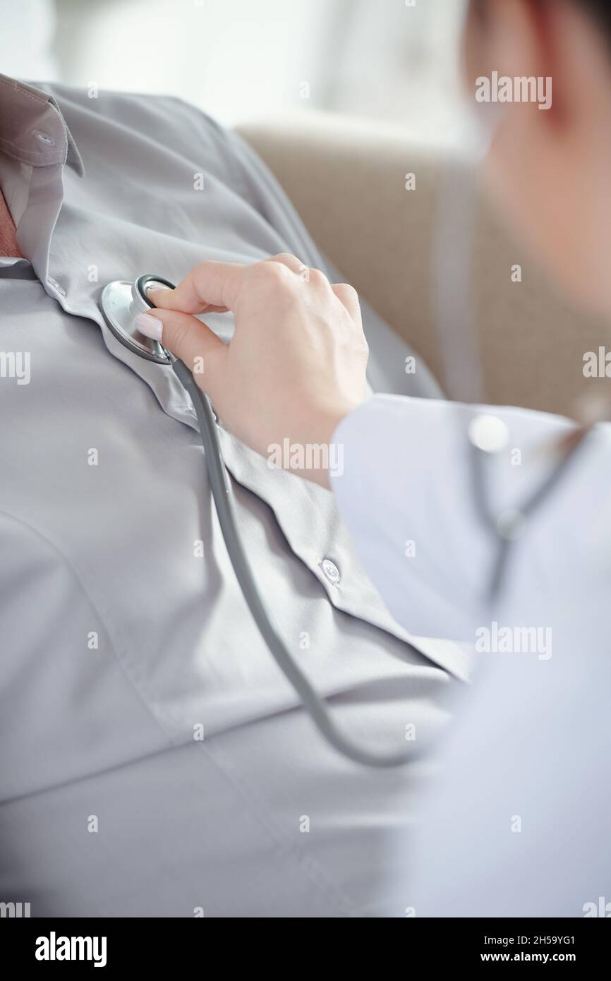 Close-up image of doctor putting chestpiece of stethoscope on chest of ...