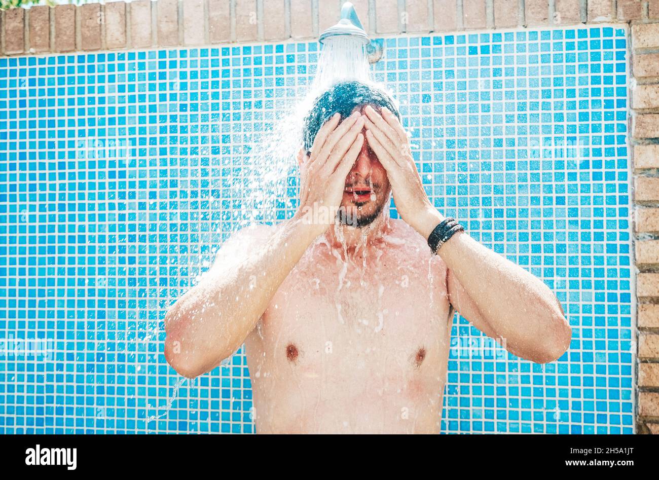 Young man having a shower before pool Stock Photo - Alamy