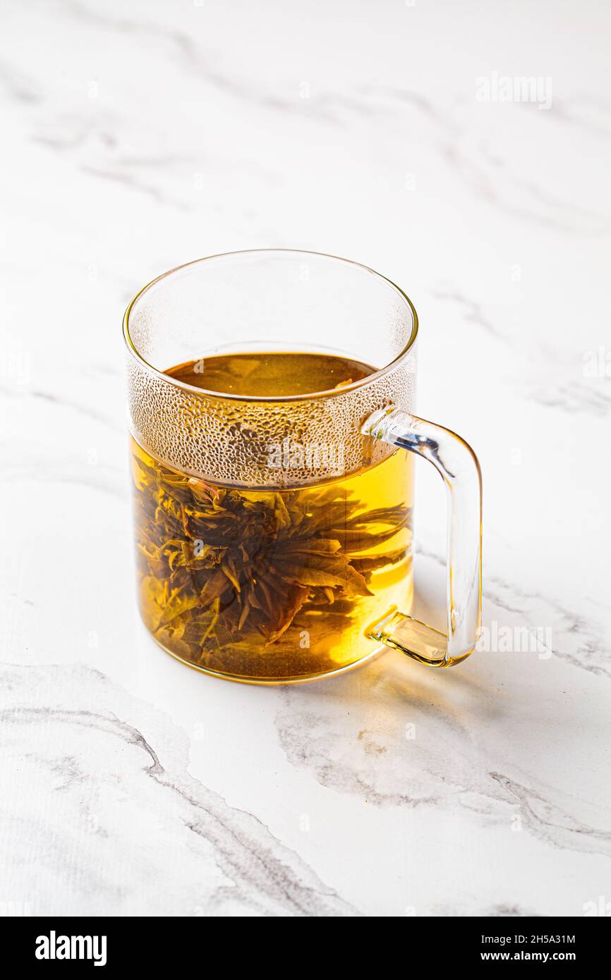 Green tea with flower ball in a glass cup, white background, copy space ...