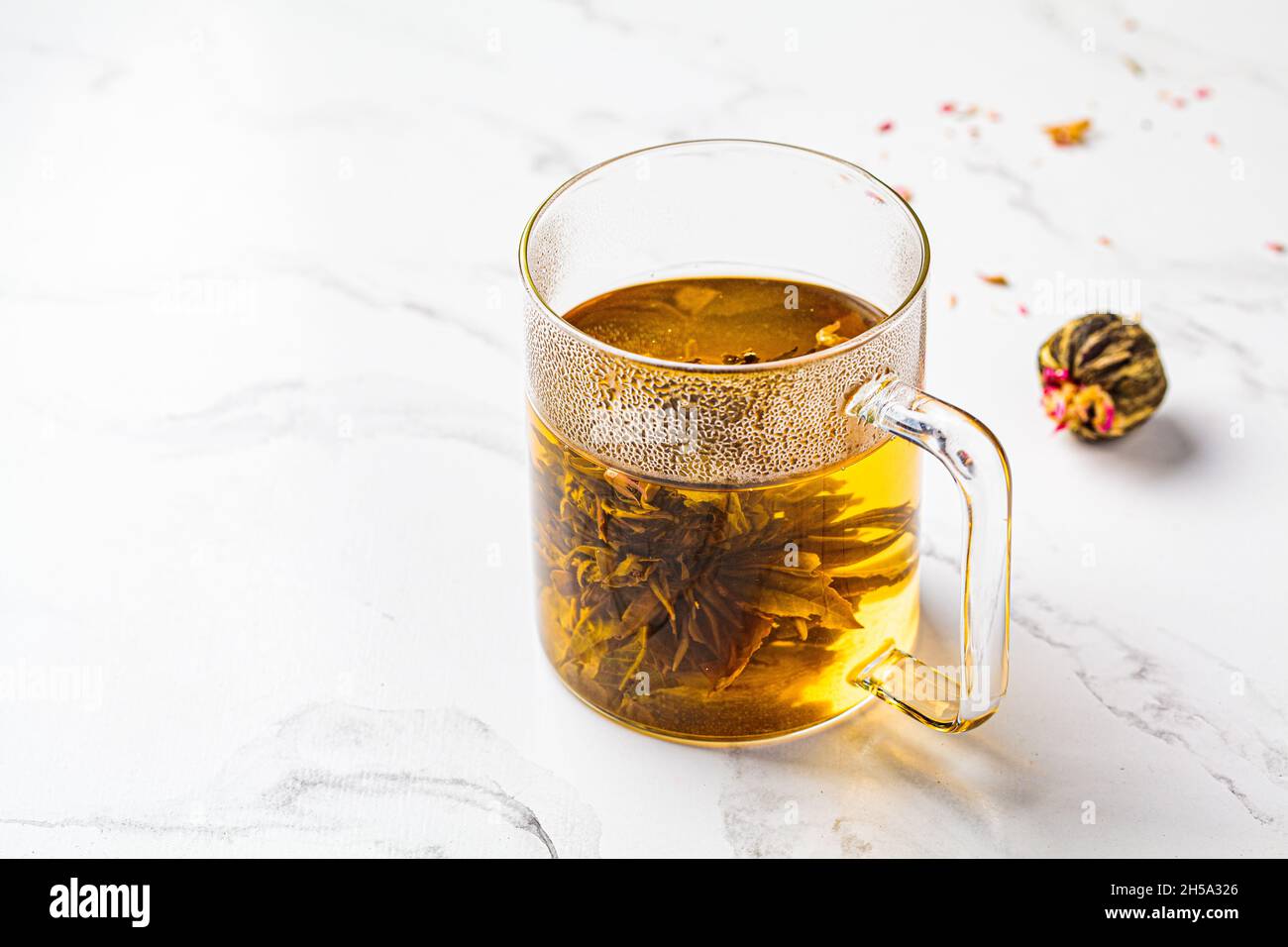 Green tea with flower ball in a glass cup, white background, copy space ...