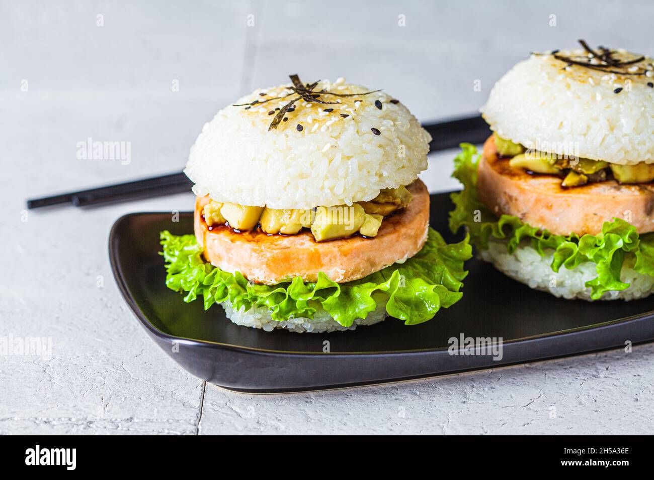 Rice burger with salmon cutlet, avocado and soy sauce, gray background ...