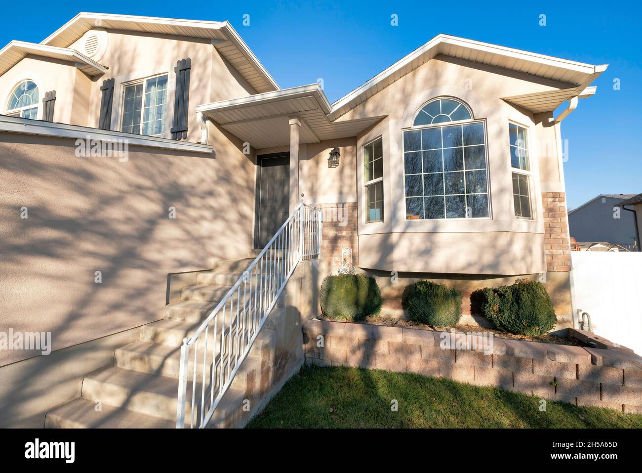 Exterior of a two storey house with stairs leading to a front gray door ...