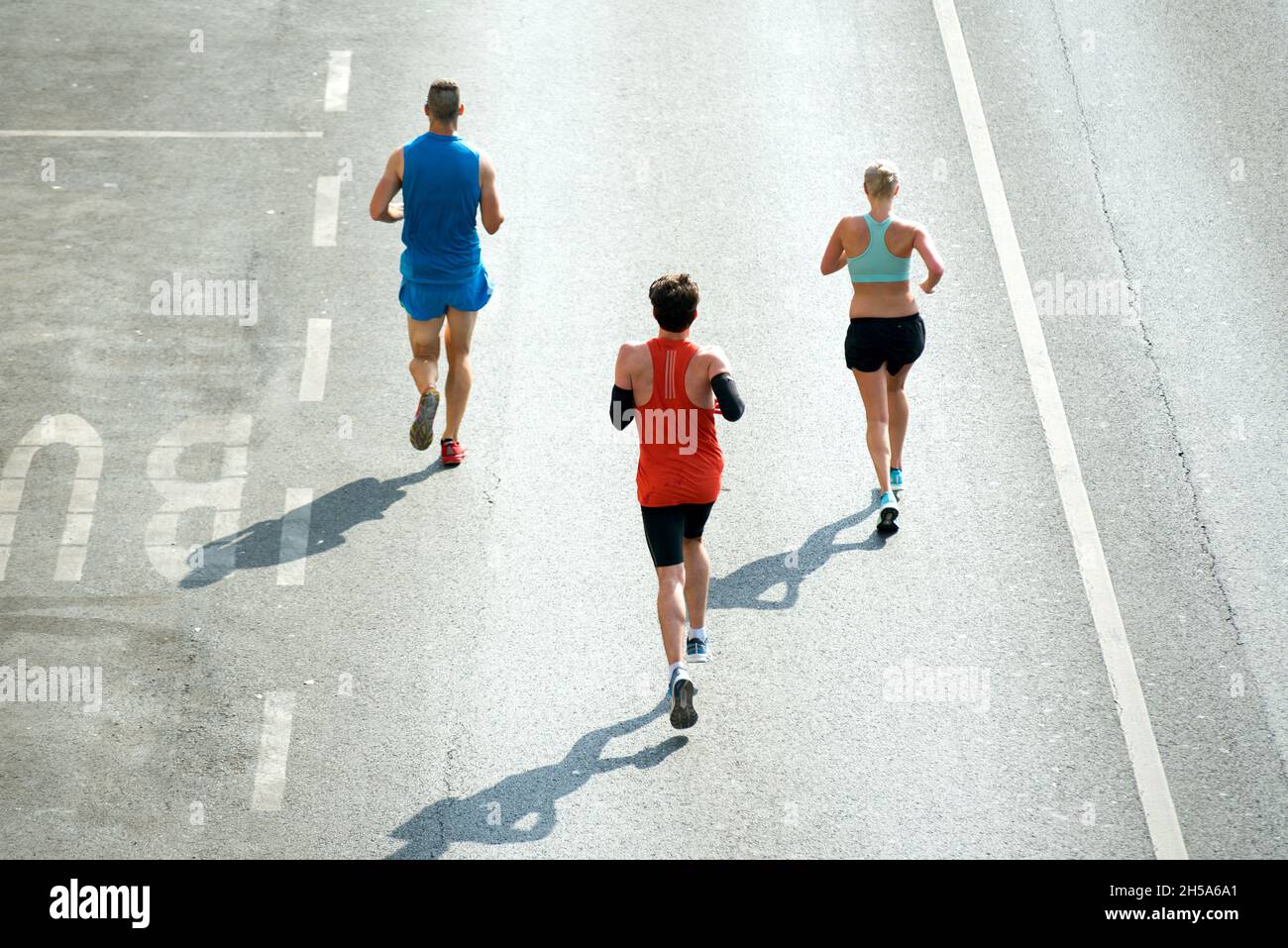 Three person running on the asphalt road, rear view Stock Photo - Alamy