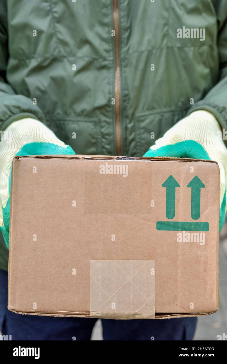 Courier is holding a parcel with a fragile symbol on a cardboard box ...