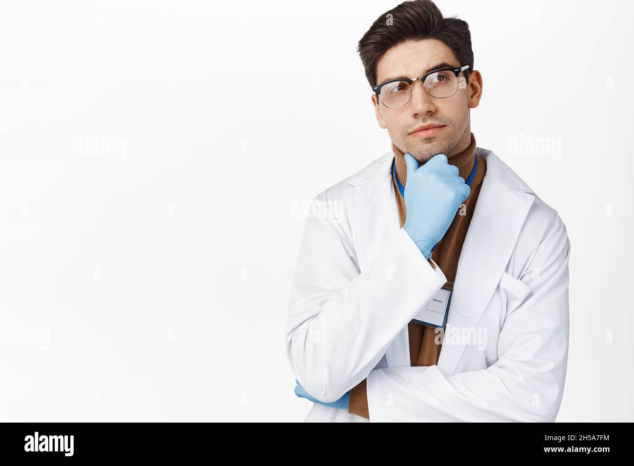 Image of doctor in glasses and medical gloves thinking, looking up with ...