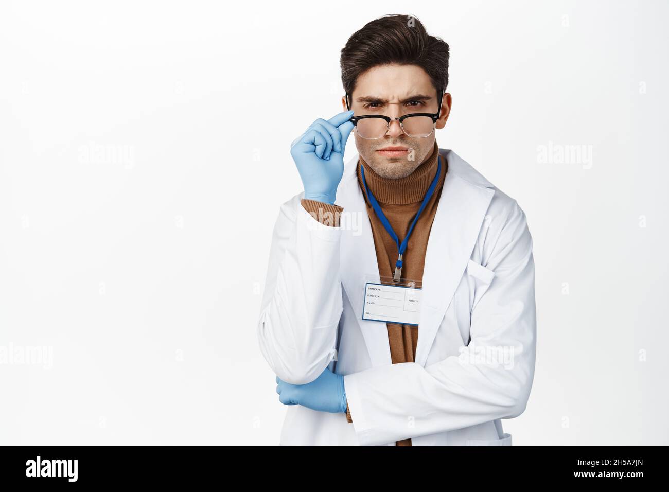Suspicious doctor frowning and squinting, looking with glasses at smth ...