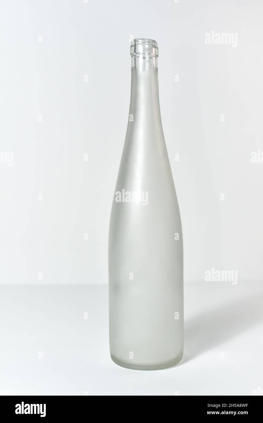 empty wine bottle without label standing on a table against a white ...
