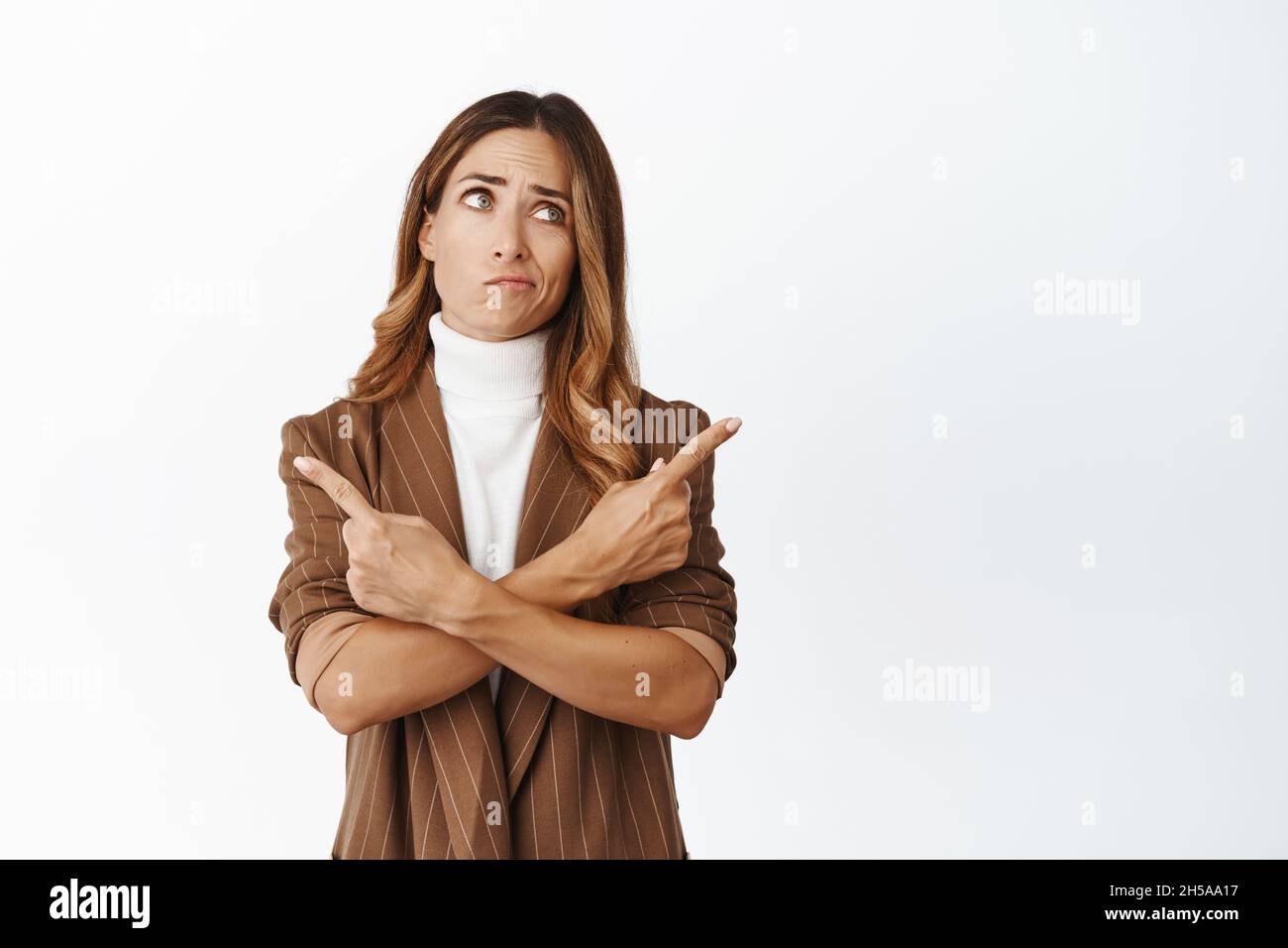 Portrait of indecisive woman pointing sideways with confused face ...