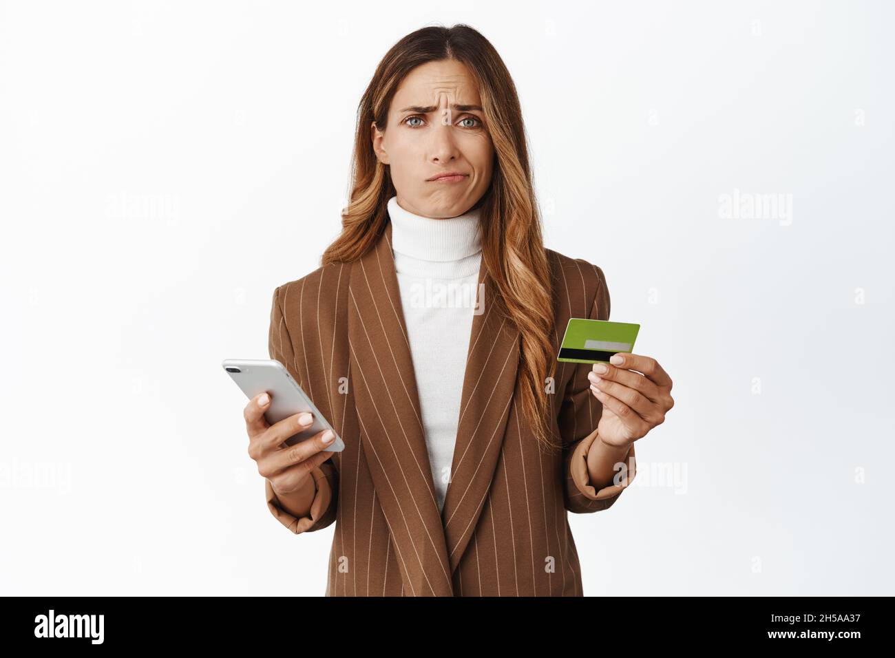 Sad and disappointed woman holding credit card and smartphone, bad user ...