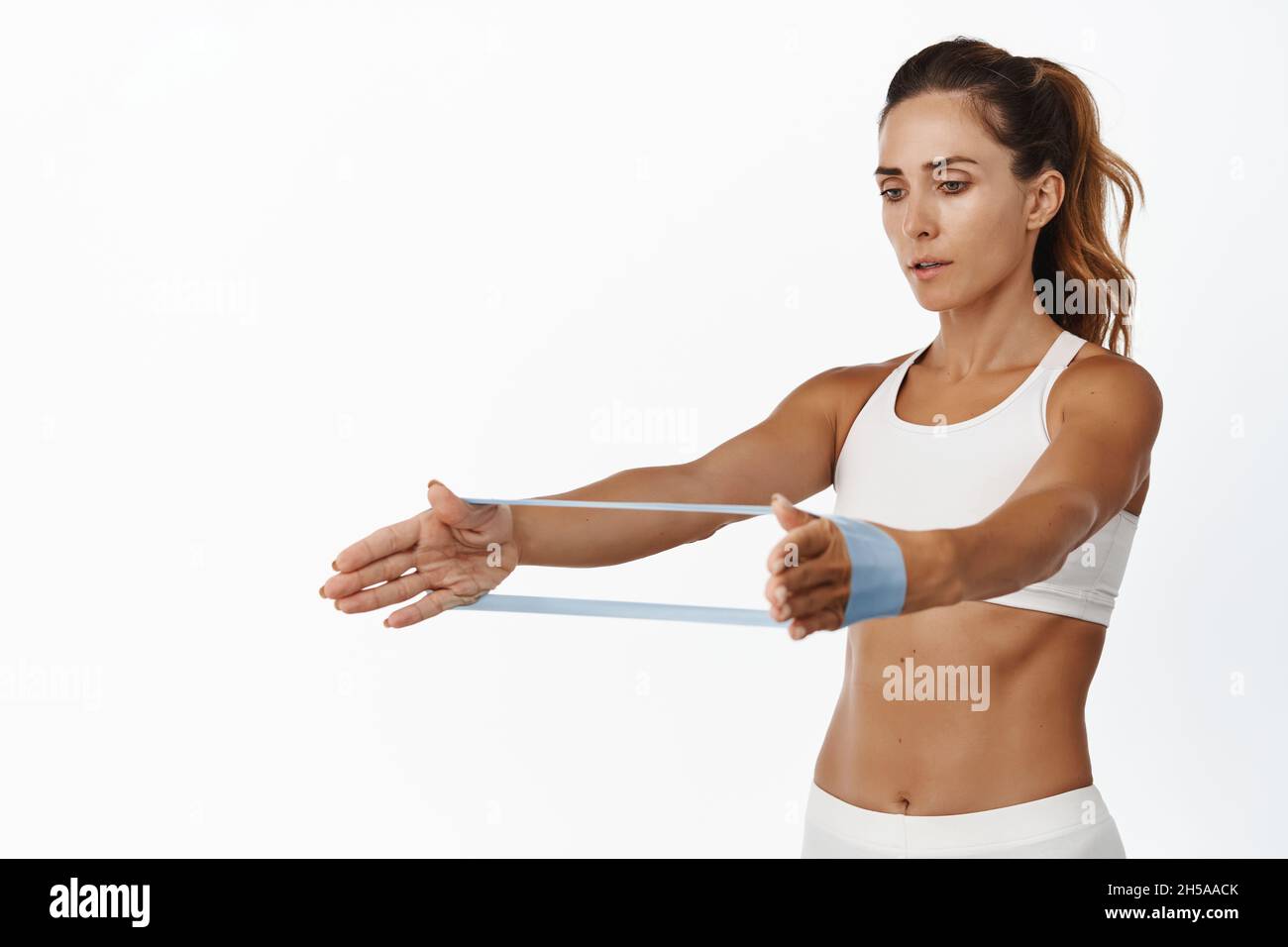 Image of focused female athlete using stretching rope, elastic band ...