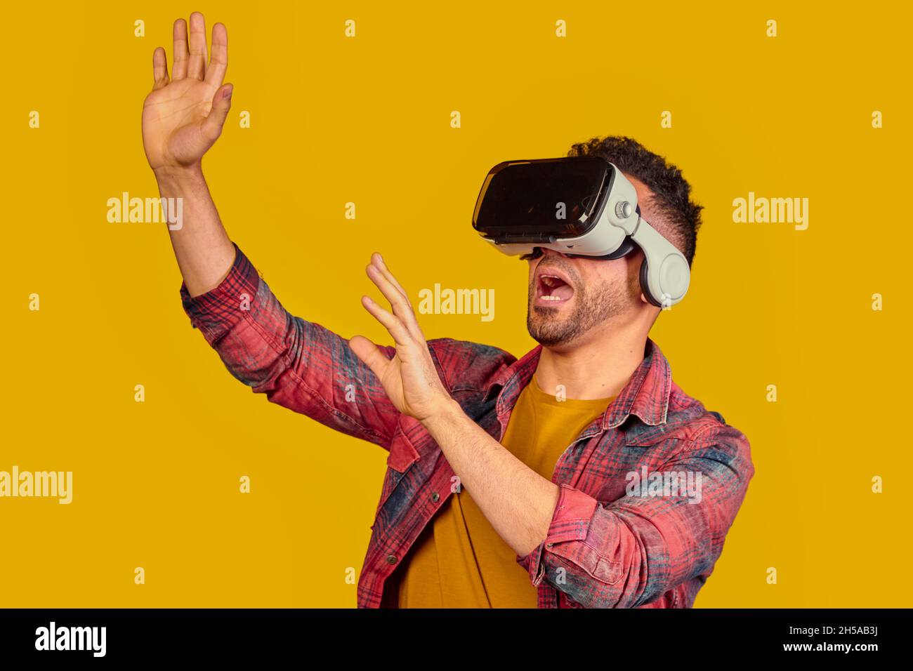Man having fun with virtual reality glasses. Studio shot, yellow ...