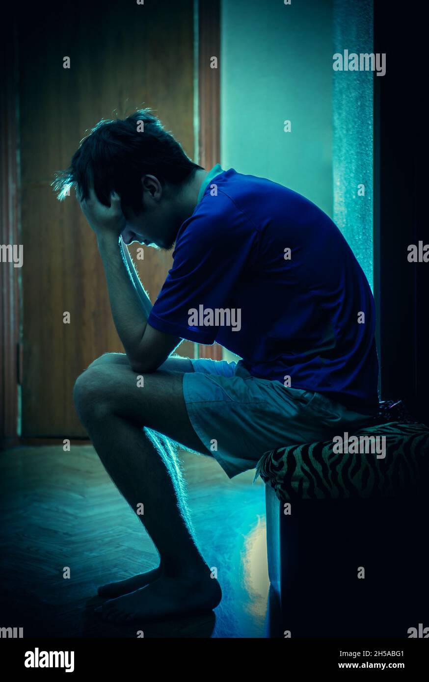 Toned Photo of Sad Young Man sit in the Dark Room Stock Photo - Alamy