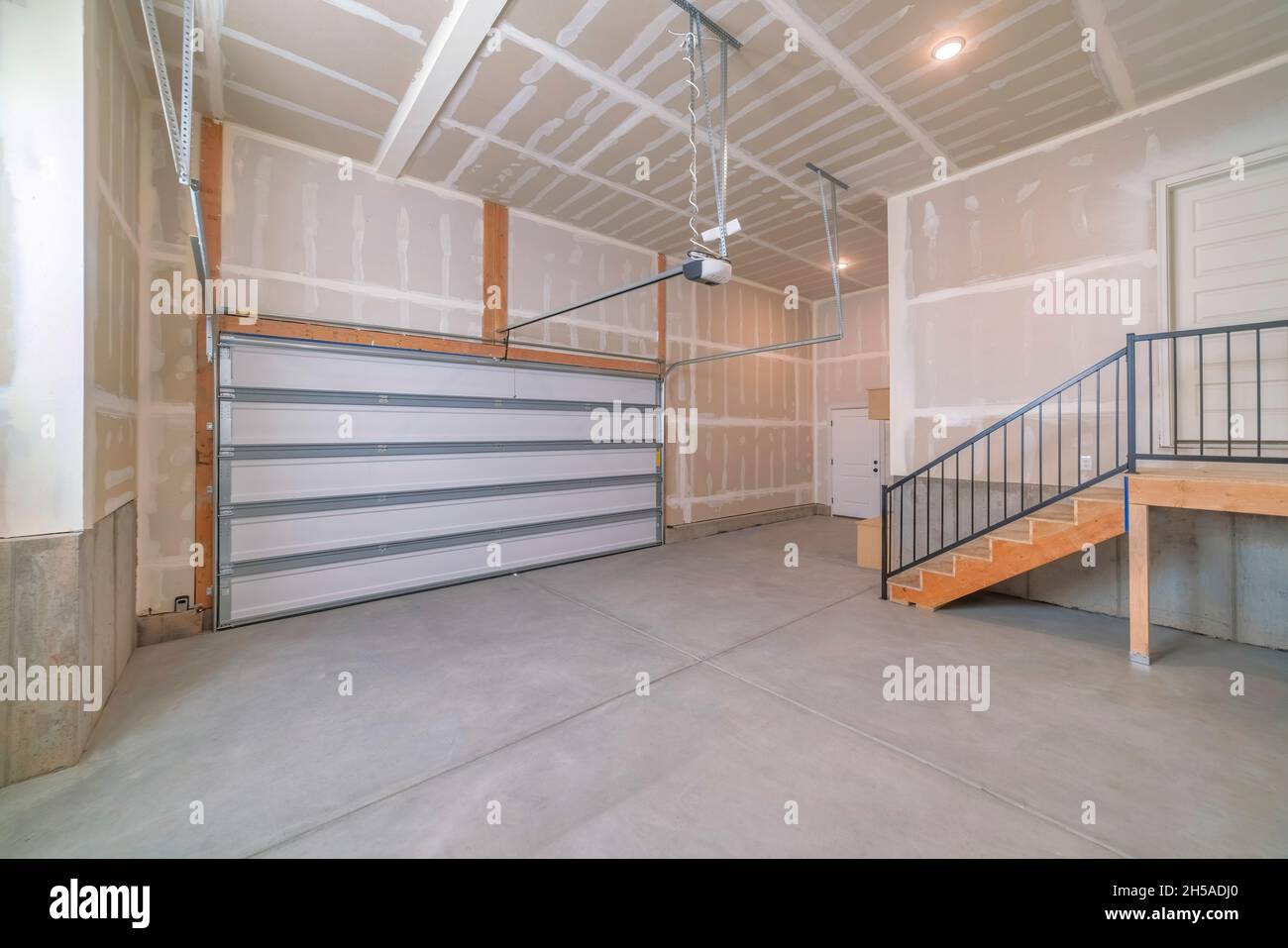 Interior of an unfinished garage with automatic white sectional door ...
