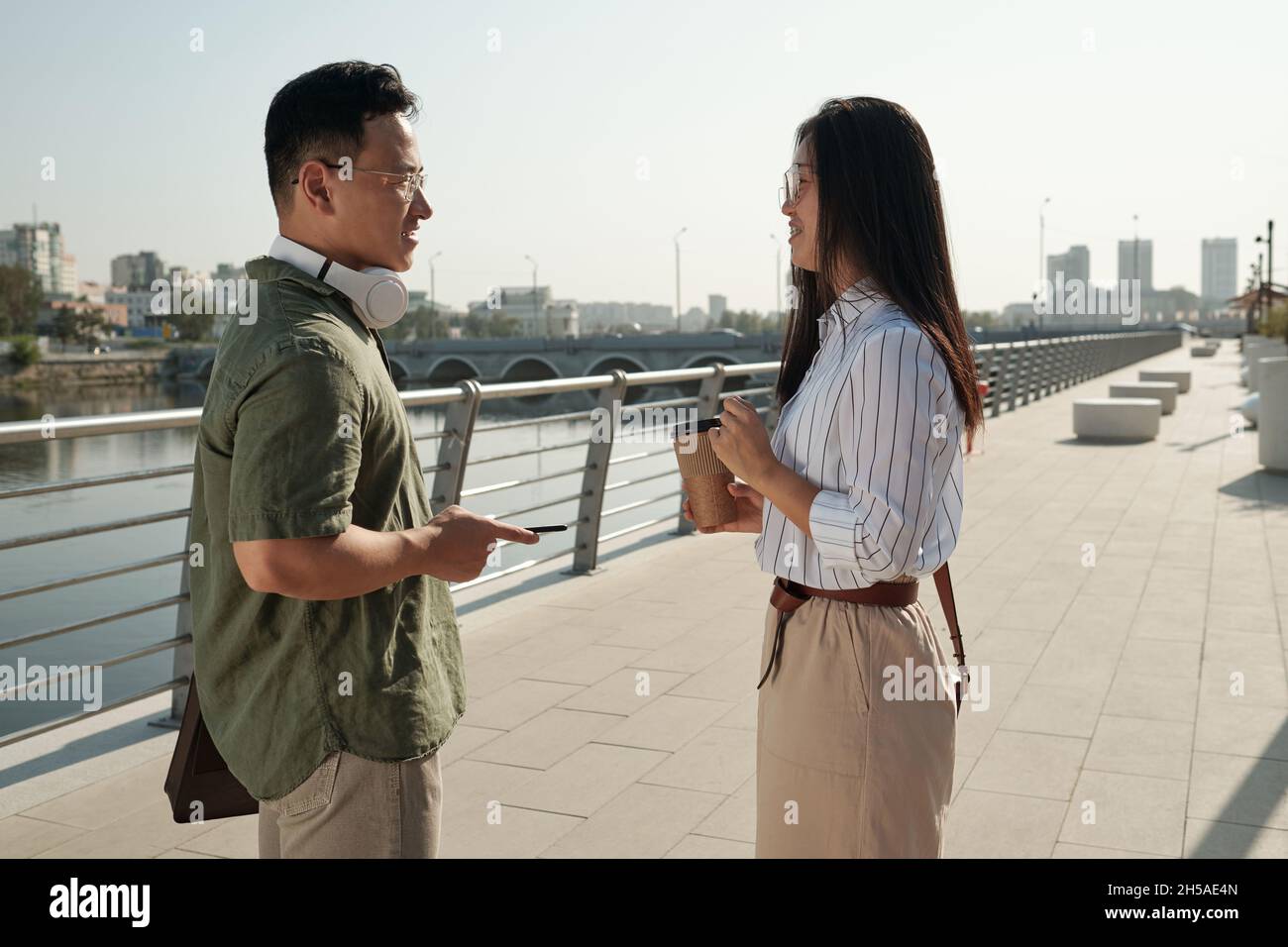 Two happy young Asian colleagues having discussion of working points ...