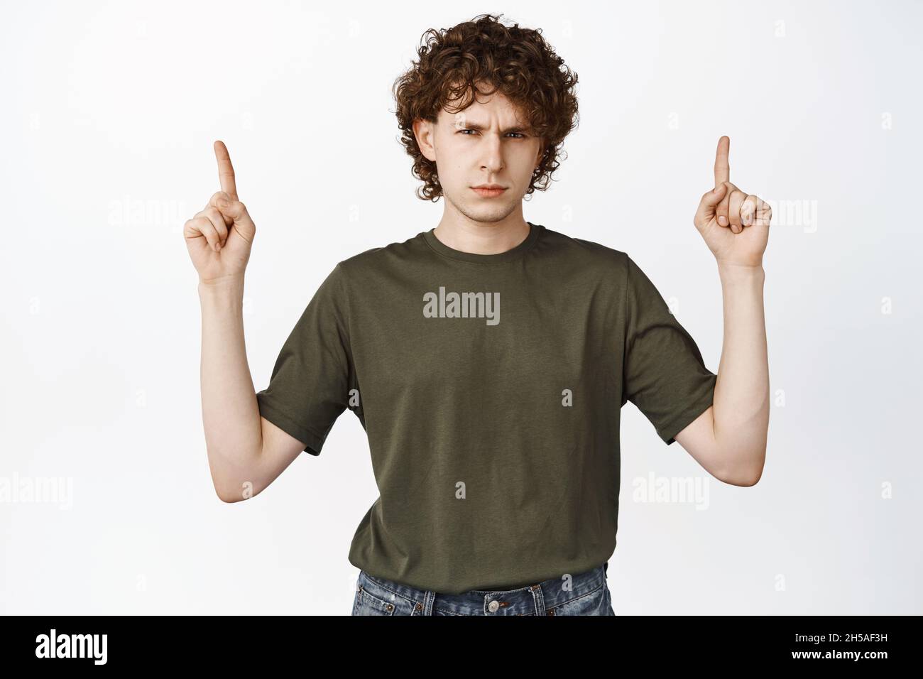 Suspicious guy squints, points fingers up and looks with disbelief, has ...