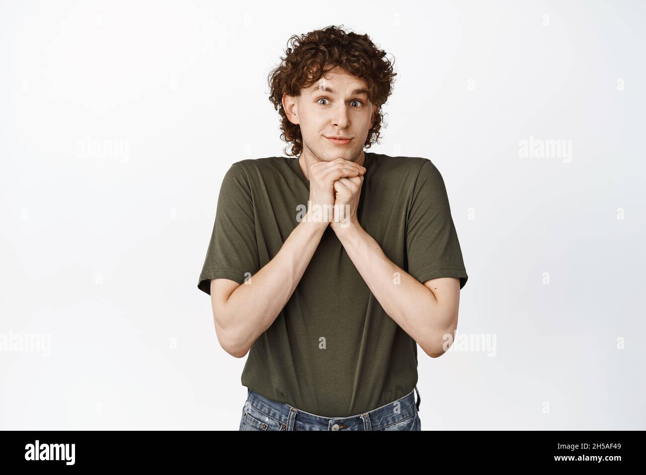 Excited cute curly-haired guy, listening and looking with fascinated ...