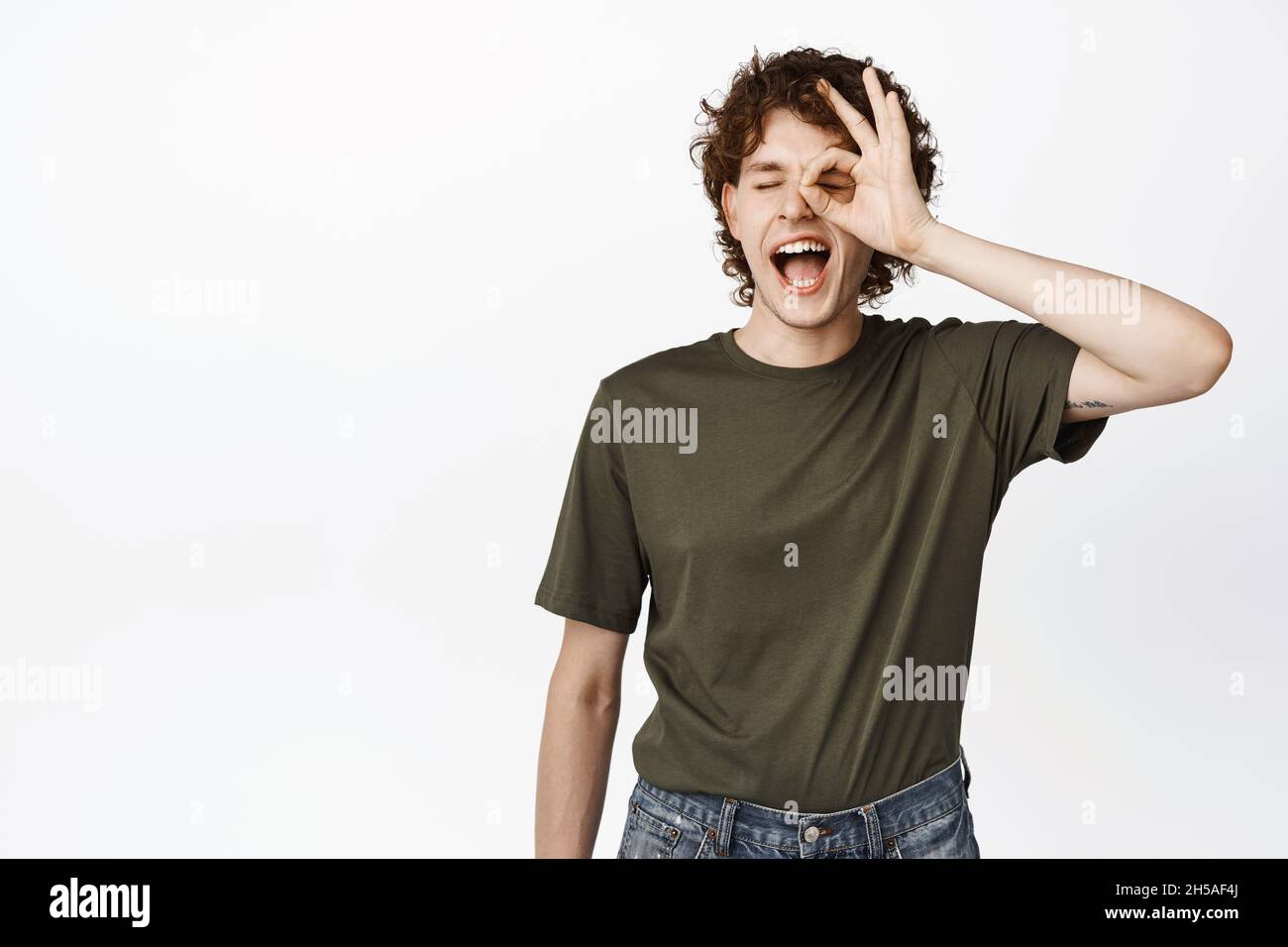 Cheerful young man showing okay, ok sign and laughing, approve ...