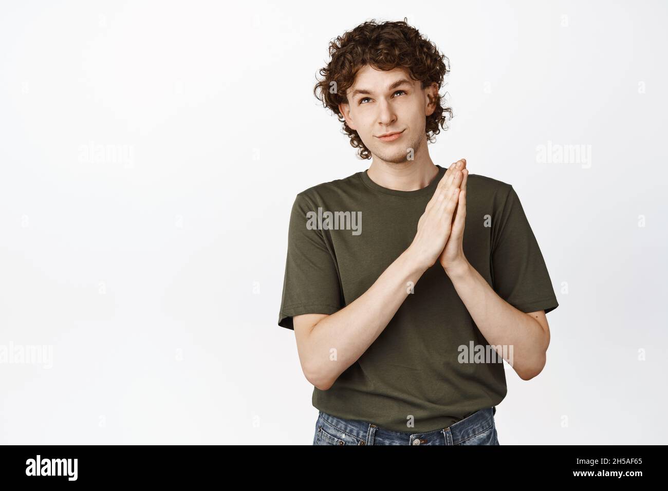 Thoughtful young man rub his hands, relish smth good, looking up ...