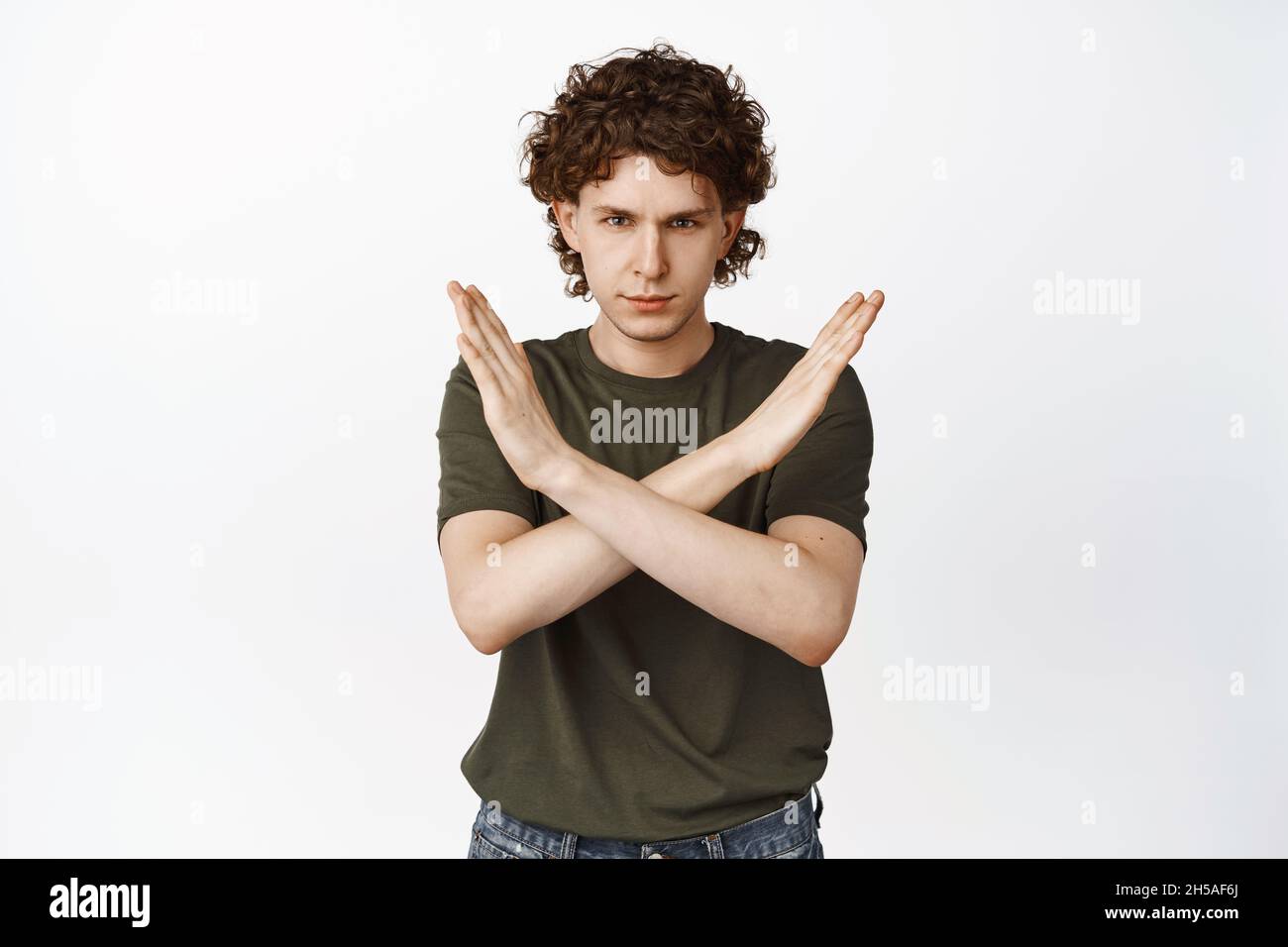 Serious and confident curly man making cross gesture, prohibit smth ...